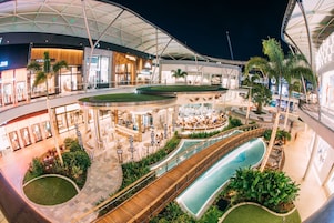 Um complexo moderno em ambiente interno com piscina central, vários níveis e áreas de estar ao ar livre.