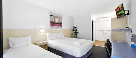 Quarto de hotel com duas camas, uma escrivaninha, uma cadeira, uma televisão e um quadro na parede.