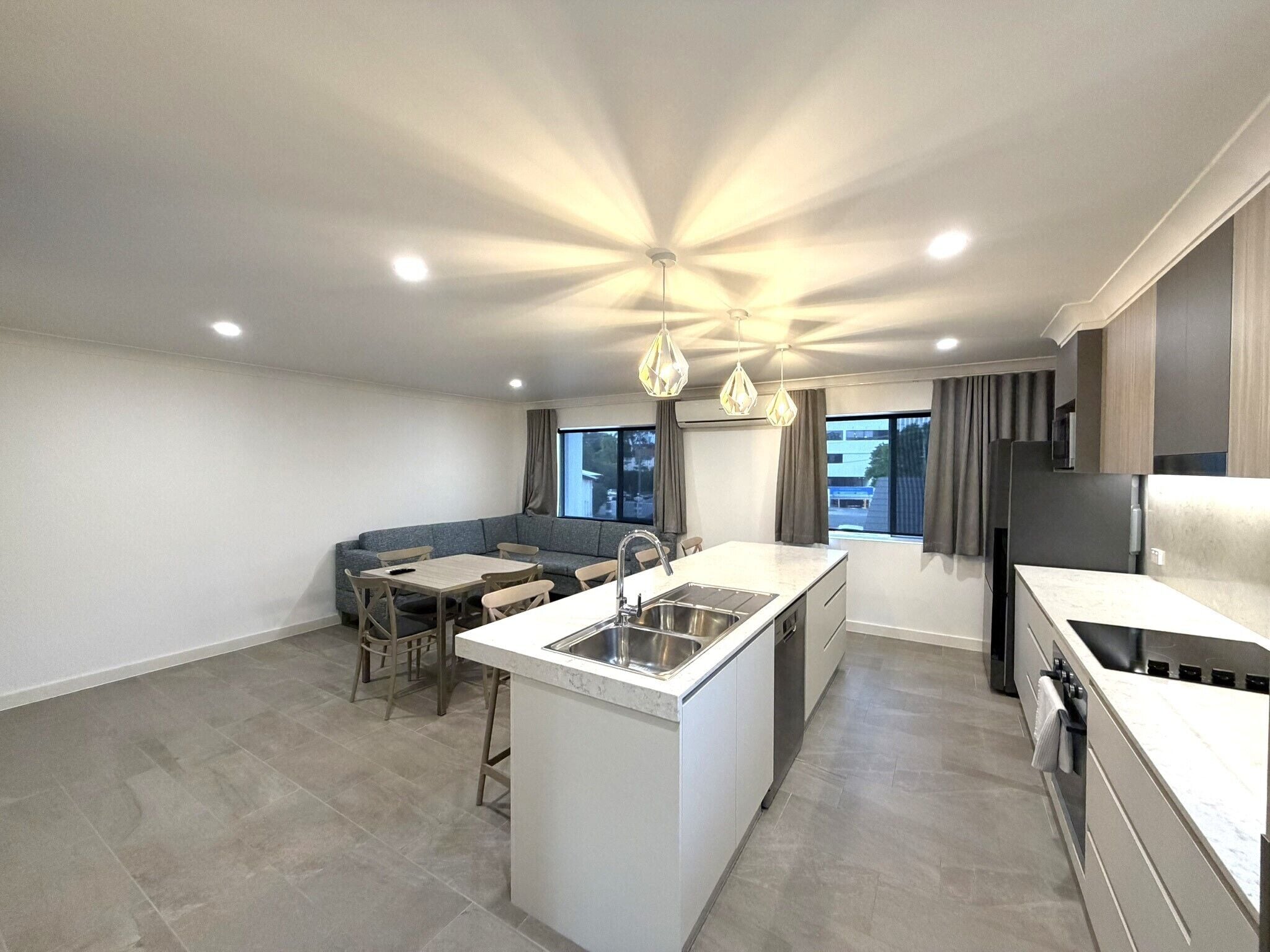 Uma cozinha moderna com uma ilha central, uma área de refeições com um sofá e vista para o exterior.