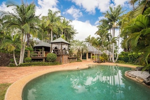 Um resort com piscina, palmeiras e um gazebo.
