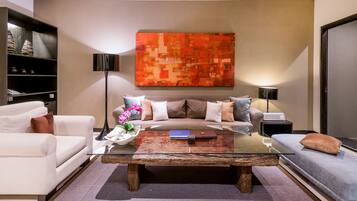 Uma sala de estar moderna com um sofá, uma mesa de centro e uma grande pintura abstrata na parede.