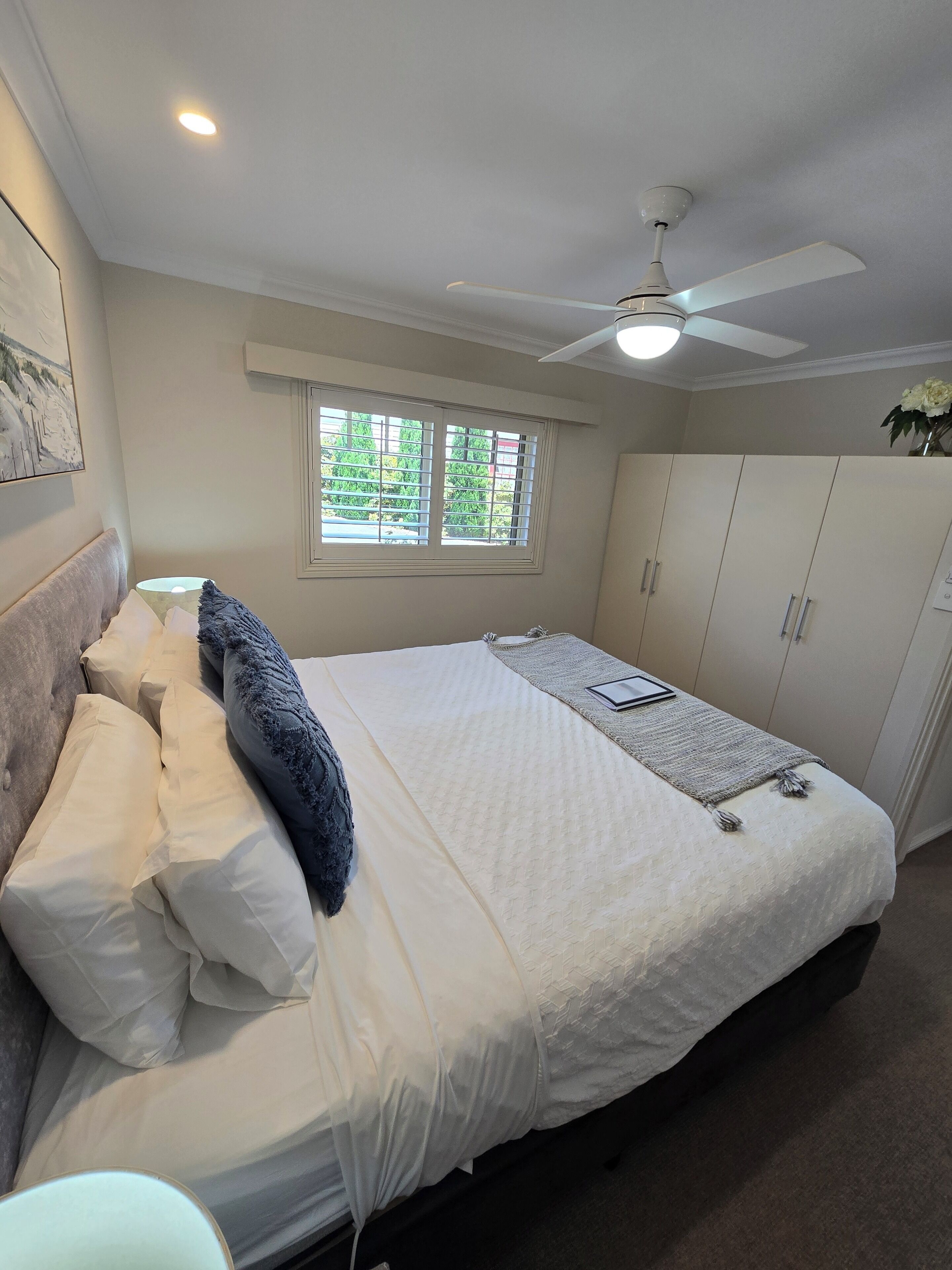 Quarto com cama, ventoinha no teto, janela e armário.