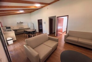 Um espaço de estar compacto com cozinha compacta, sofá, mesa de jantar e pequena área de cozinha.