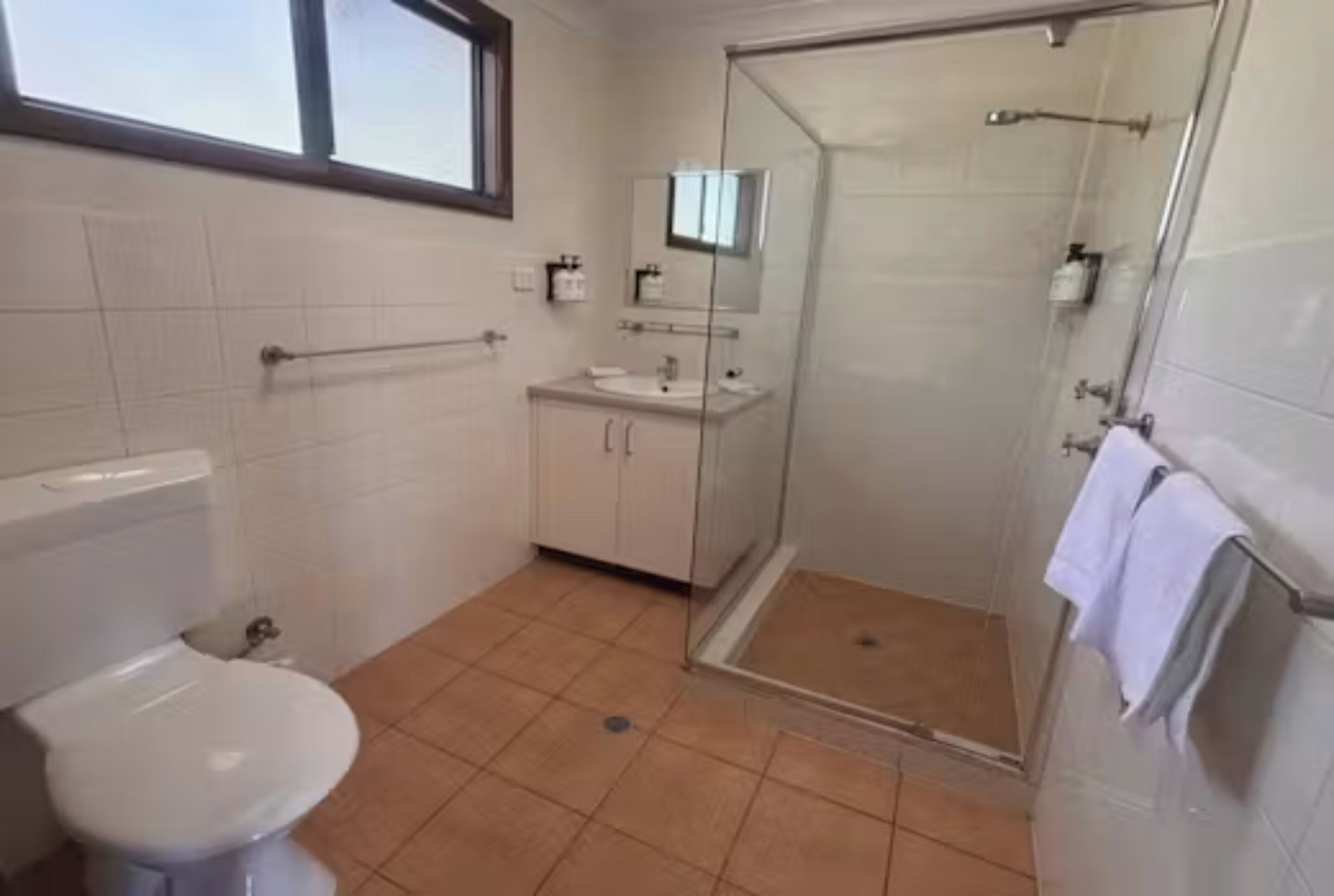 Uma casa de banho com sanita, lavatório e chuveiro.