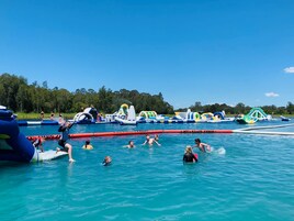 Piscina com estruturas de recreação aquática infláveis e céu azul límpido.