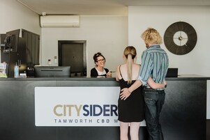 Bancada de recepção com uma placa indicando 'CITYSIDER TAMWORTH CBD'.