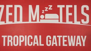 Um sinal com o texto 'ZED M Z ZELS' e 'TROPICAL GATEWAY'.