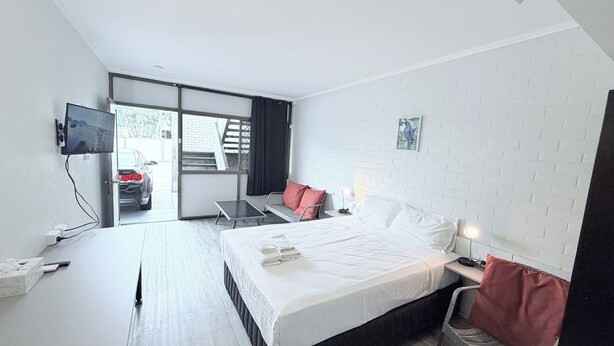 Quarto de hotel moderno com uma cama grande, escrivaninha, cadeira, televisão e vista para o exterior.