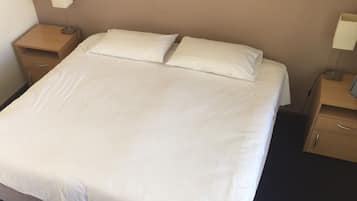 Cama bem arrumada com lençóis brancos em um quarto de hotel.