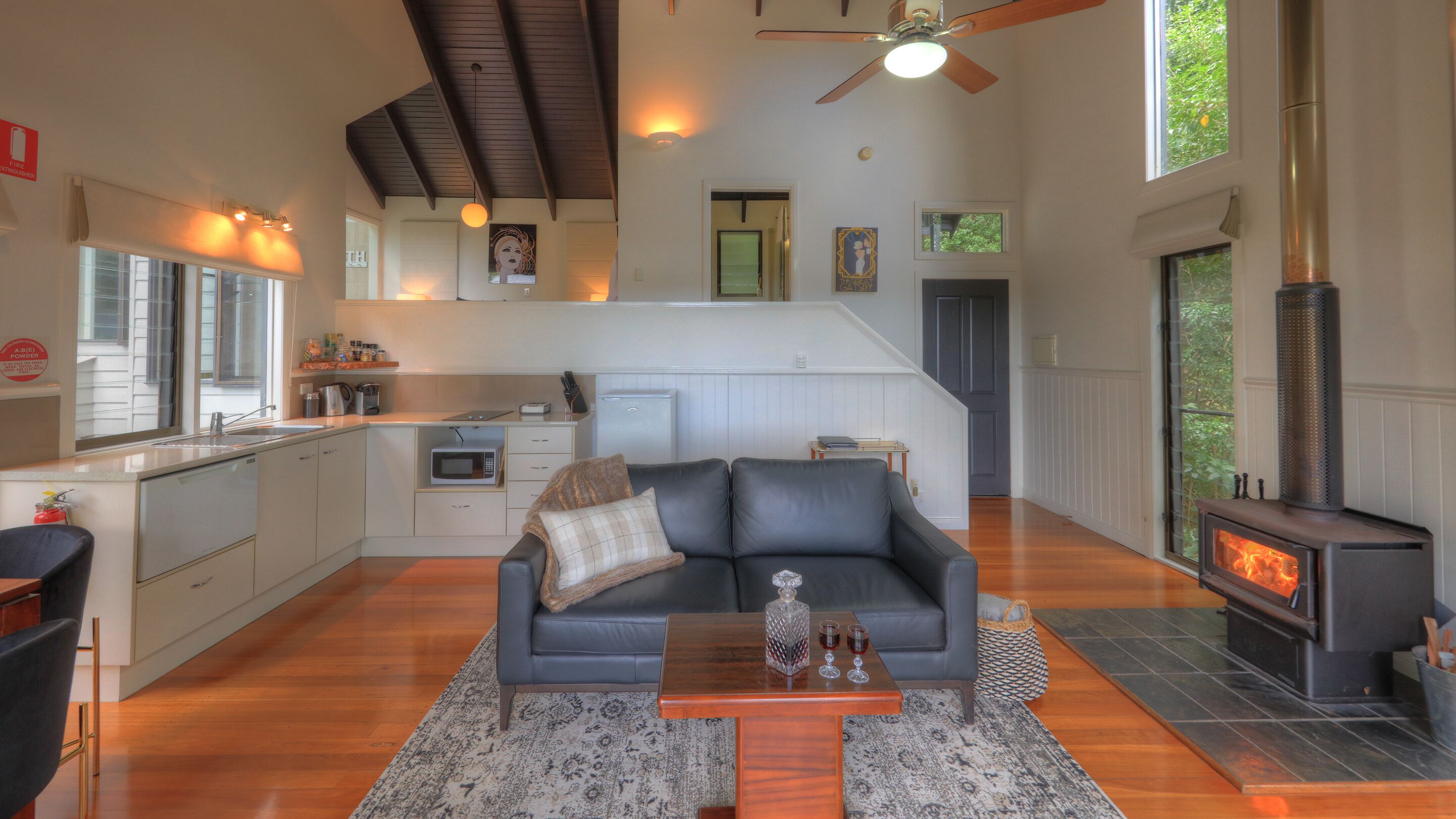 Uma sala de estar moderna com lareira, uma cozinha com micro-ondas e um espaço de jantar com mesa e cadeiras.
