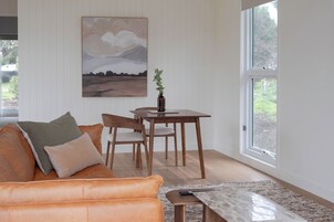 Uma sala de estar com sofá, mesa e um quadro na parede.