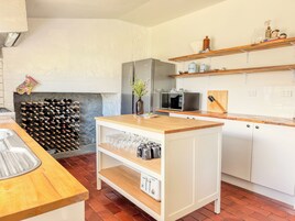 Uma cozinha moderna com adega, micro-ondas e bancada de madeira.