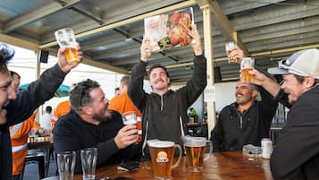 Um grupo de pessoas num bar, com canecas de cerveja e um menu.