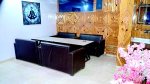 Uma sala de jantar com uma mesa e cadeiras, uma parede de madeira com padrões geométricos e um quadro fixado na parede.