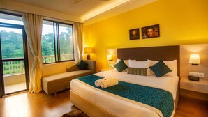 Quarto de hotel com uma cama grande, um sofá, uma varanda e duas luminárias.