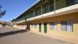 Um edifício com telhado plano, várias janelas e uma galeria coberta.