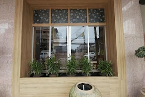 Uma janela com moldura de madeira, vários vasos com plantas e um vaso de flores.