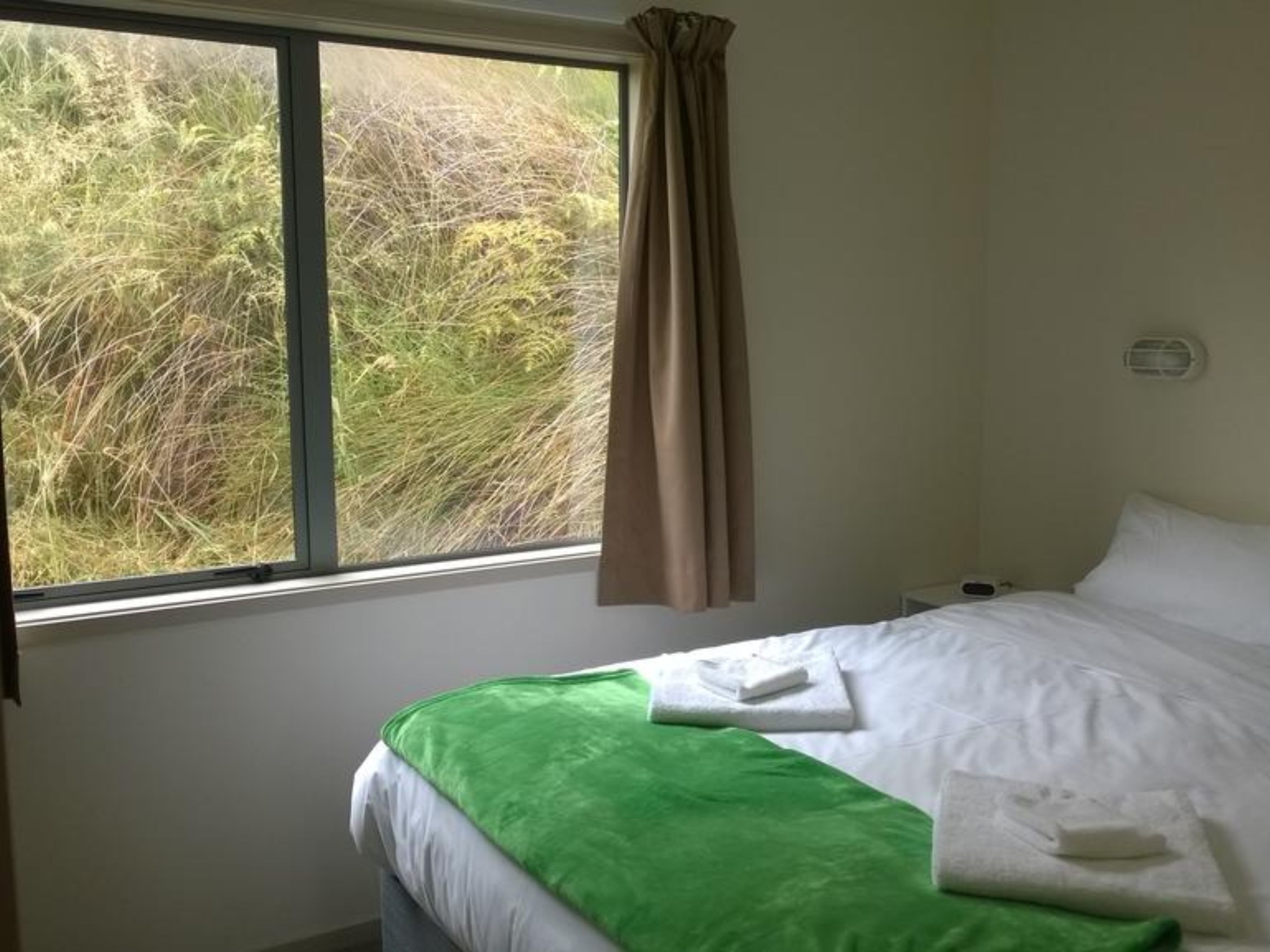 Quarto de hotel com uma cama, janela com cortinas e vista para o exterior.