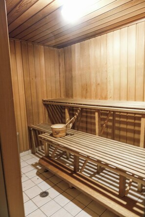 Uma sauna de madeira com bancos e um pequeno balde.