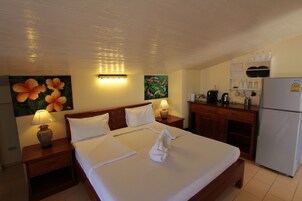 Quarto de hotel com uma cama, uma secretária pequena, um frigorífico e uma área de cozinha.