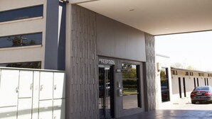 Um edifício moderno com área de recepção, estacionamento e galeria coberta.