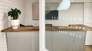 Uma receção com um vaso de planta branca, uma obra de arte emoldurada e um letreiro que diz 'RECEPTION'.