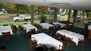 Restaurante com várias mesas e cadeiras, vista para a rua e placa indicando o Golden L Motel.