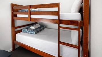 Uma cama beliche com roupa de cama branca e almofadas listradas.