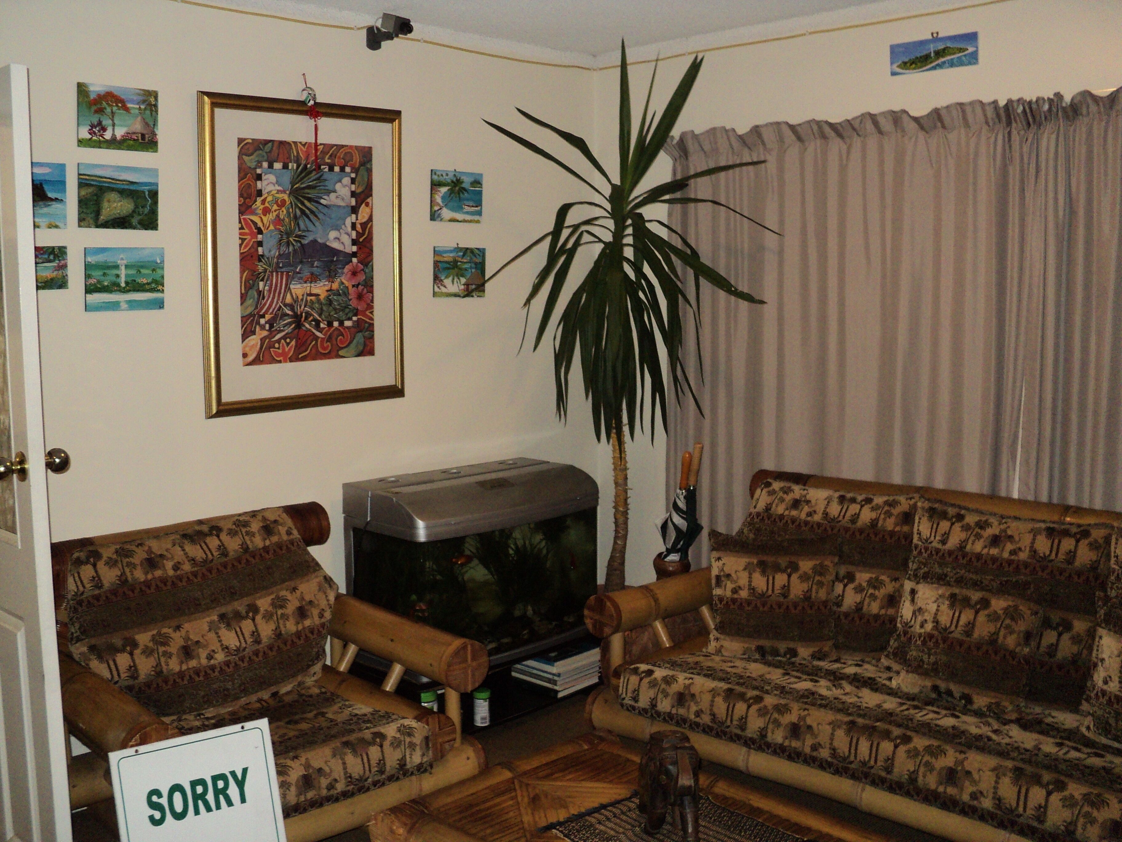 Uma sala de estar com um sofá, uma televisão e um aviso de 'Sorry' no chão.