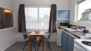Uma cozinha compacta com mesa e cadeiras, micro-ondas, pia e armários.