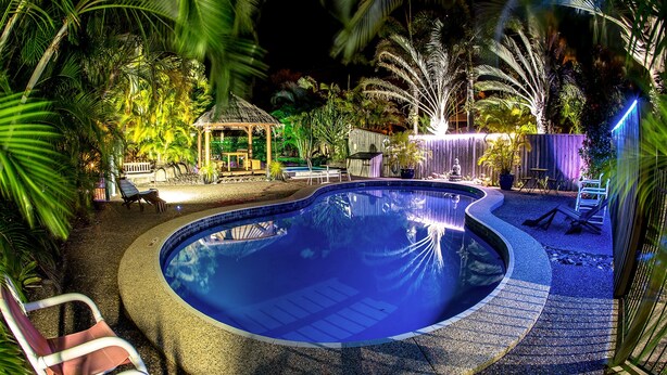 Piscina cercada por palmeiras e um gazebo.