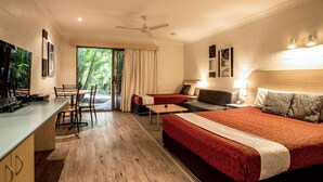 Quarto de hotel com uma cama, uma mesa de escritório, uma cadeira, uma mesinha e uma televisão.