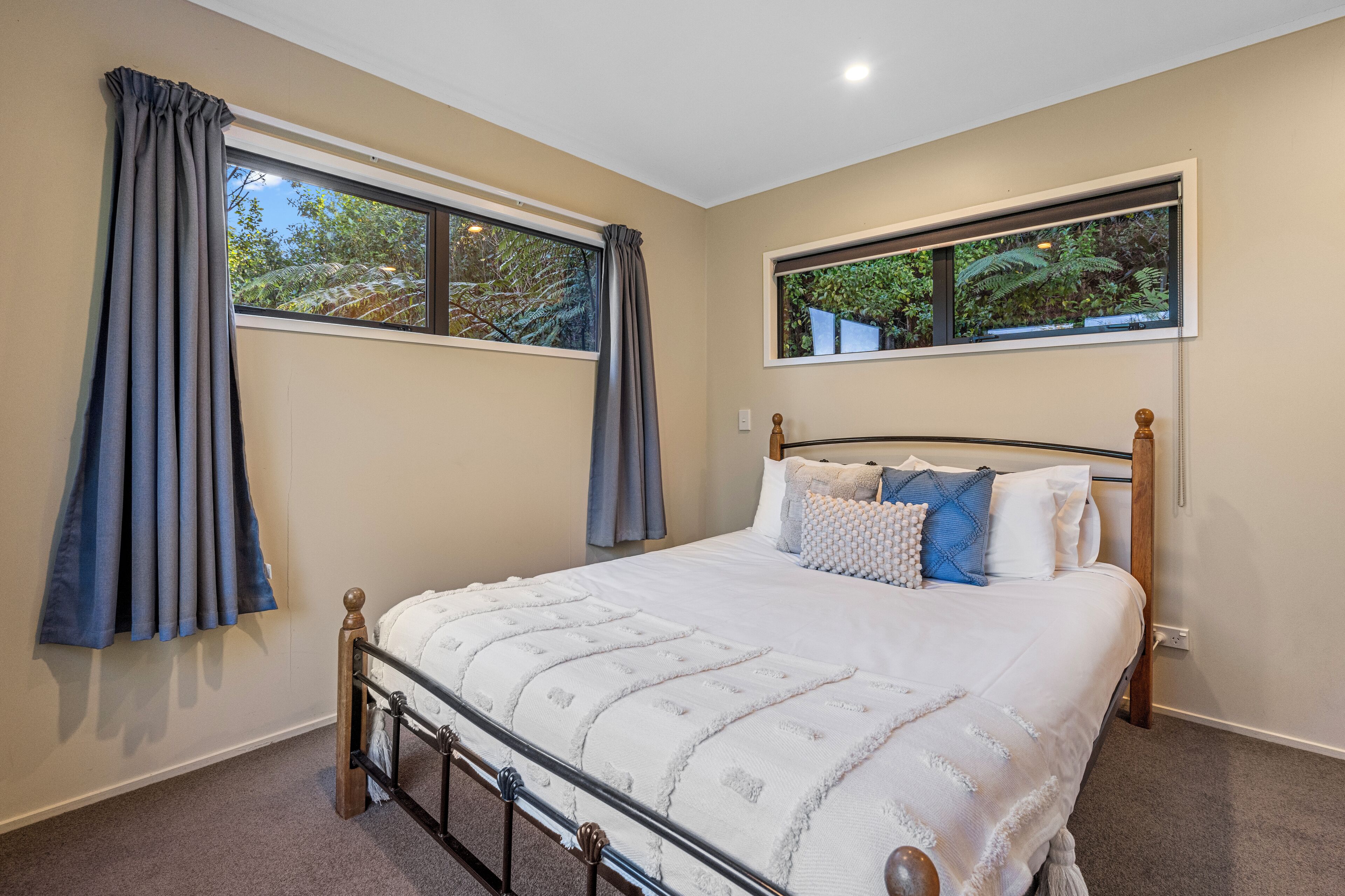 Quarto com uma cama, duas janelas e cortinas.