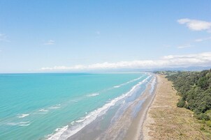 Paisagem costeira com praia e área arborizada.