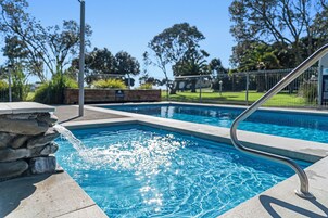 Piscina com parede de pedra e corrimão de metal.