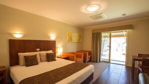 Quarto de hotel com uma cama grande, uma escrivaninha, uma cadeira e vista para o exterior.