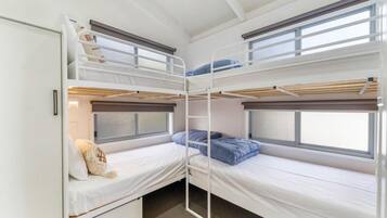 Um quarto compacto de motorhome com duas beliches, uma janela pequena e uma porta.