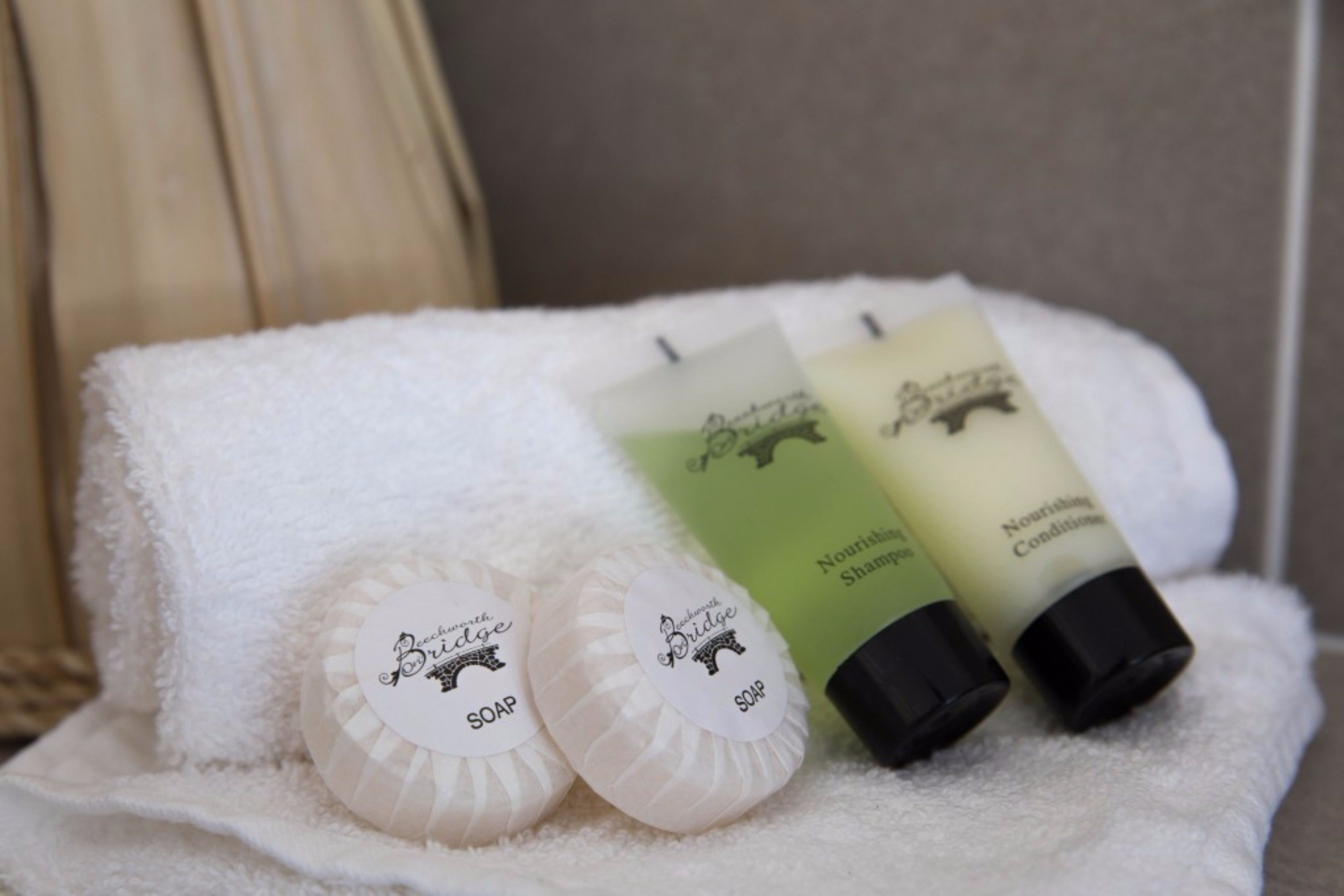 Artigos de higiene pessoal, incluindo sabonete e shampoo, sobre uma toalha branca.