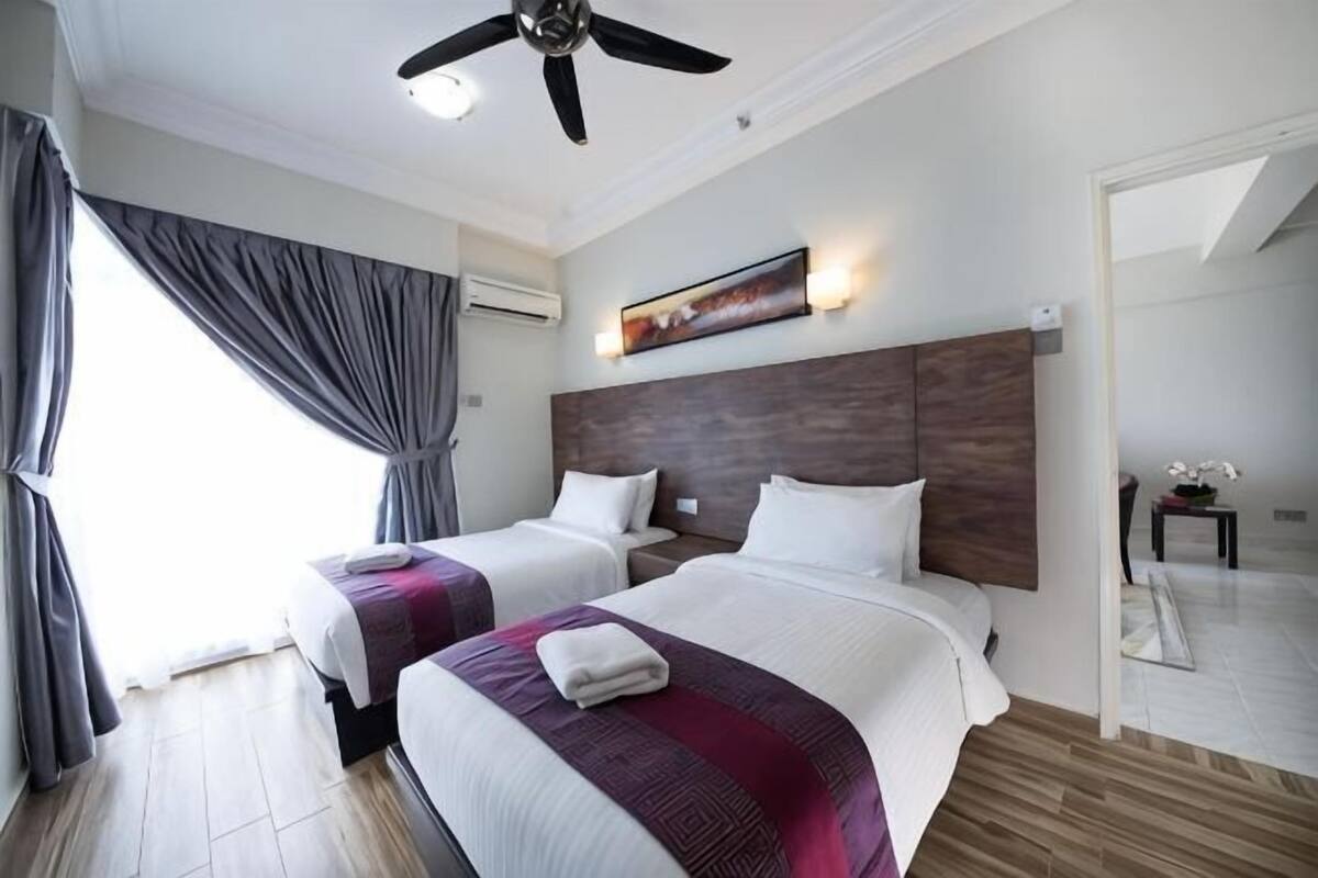Quarto de hotel com duas camas, um ventilador de teto, um quadro na parede e vista para o exterior.