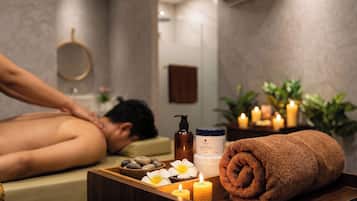 Ambiente de spa com mesa de massagem, velas e produtos para banho.