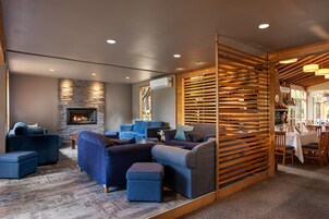 Uma sala de estar moderna com lareira de pedra, sofás azuis e um painel de madeira.