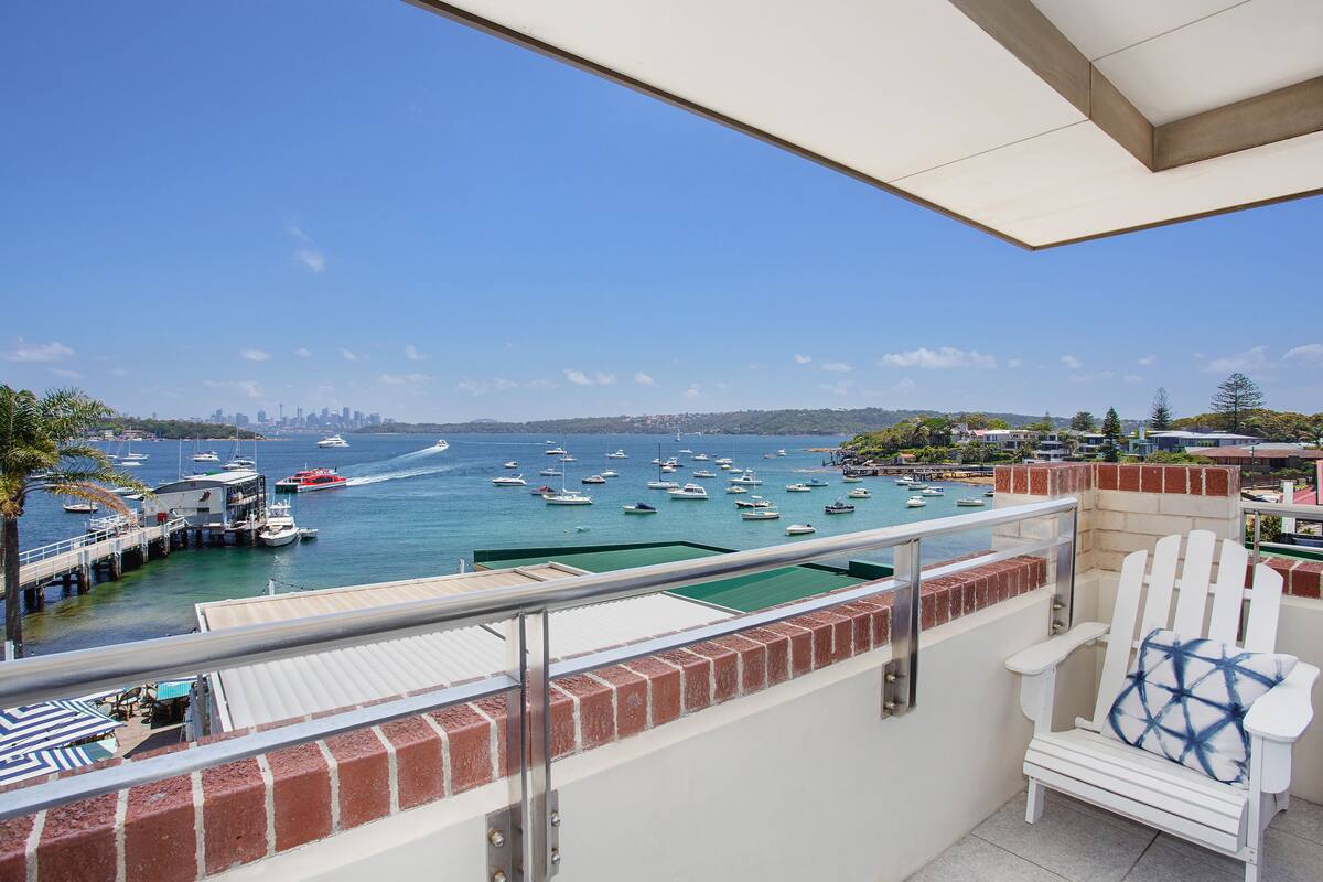 Uma varanda com vista para uma marina, barcos e o horizonte distante da cidade.