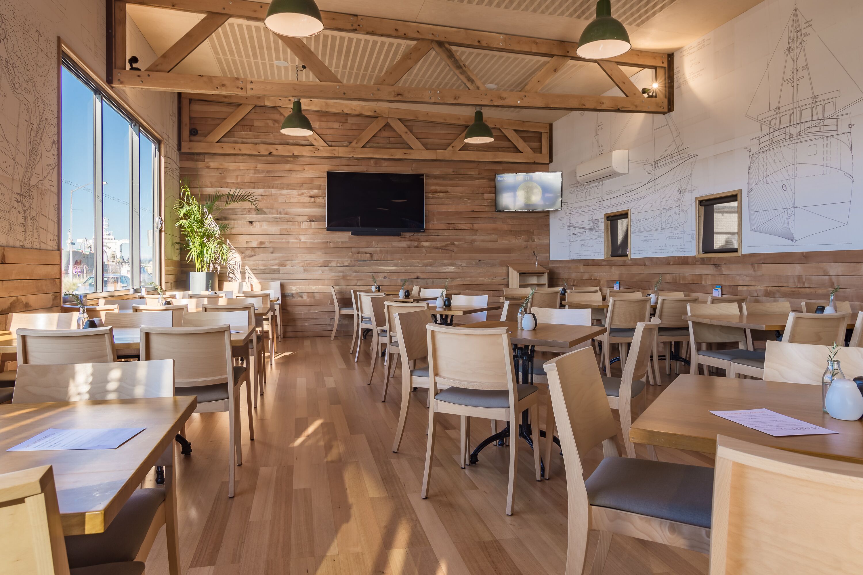 Restaurante com paredes de madeira, amplas janelas e uma televisão fixada na parede.