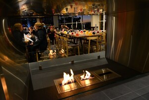 Uma sala de jantar moderna com uma mesa comprida, cadeiras e uma lareira central.