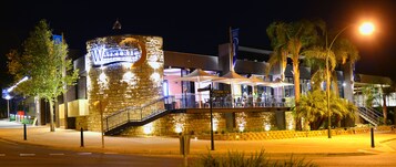 Um hotel com fachada de pedra, área de estar ao ar livre e escadaria que leva à entrada.