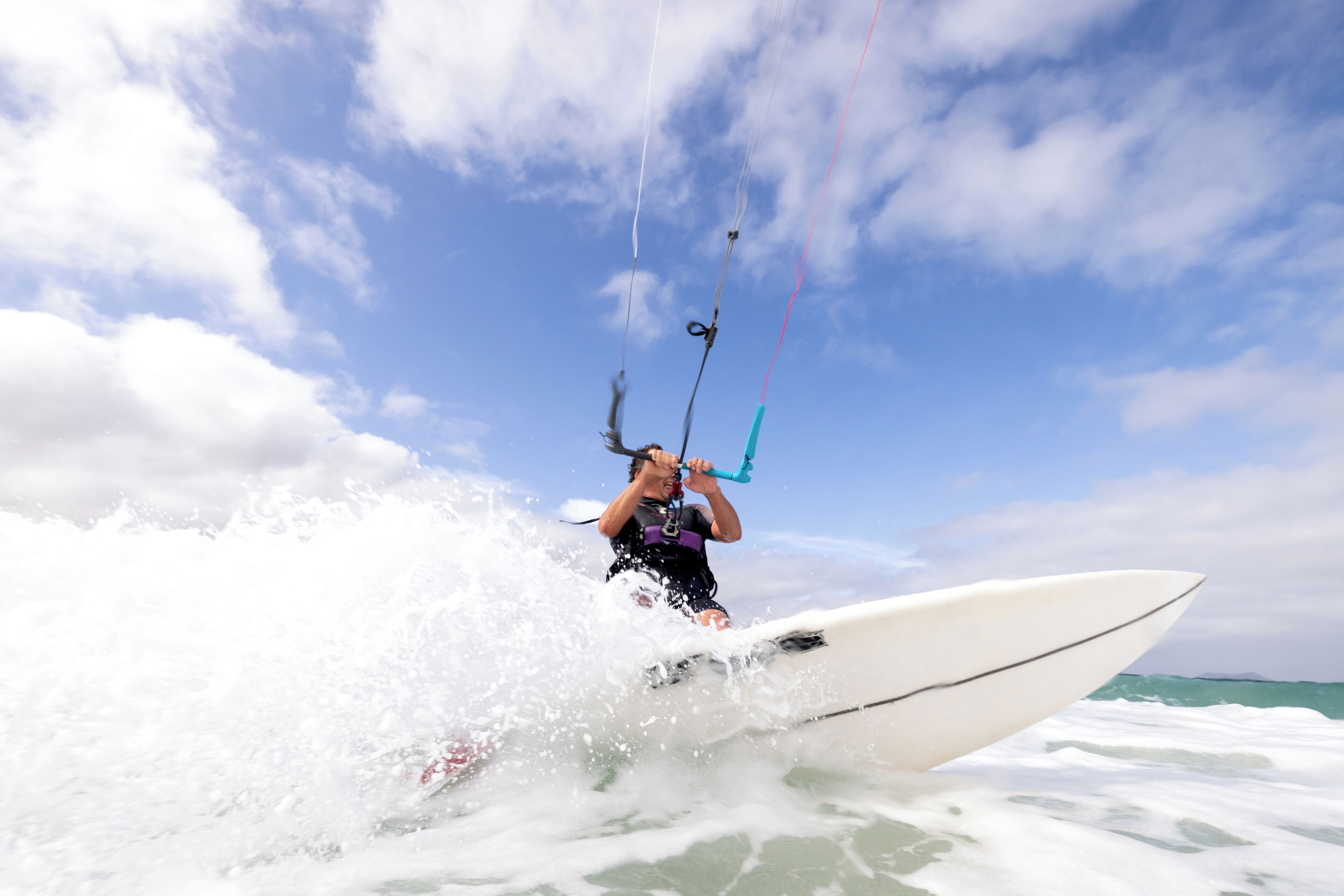 Uma pessoa surfando na água, com um céu azul claro ao fundo.