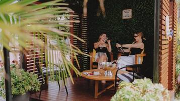 Espaço ao ar livre com mobiliário de madeira e uma mesa com uma tigela de vidro.