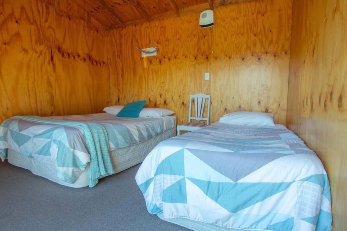 Uma cabana de madeira com duas camas, cada uma com colcha de padrão geométrico.