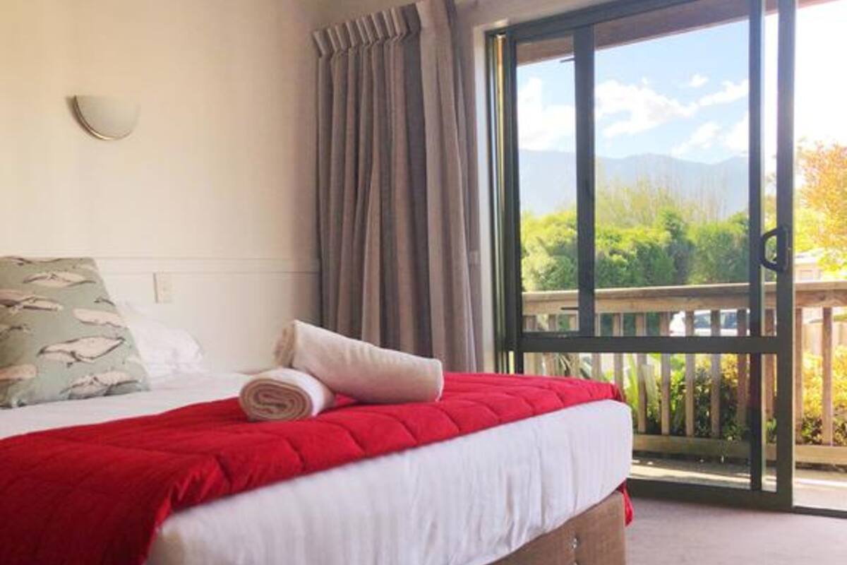 Quarto com cama, vista para o verde e varanda.