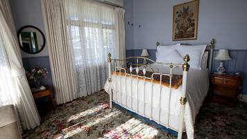 Quarto com cama, mesa de cabeceira, penteadeira, espelho e janela com cortinas.